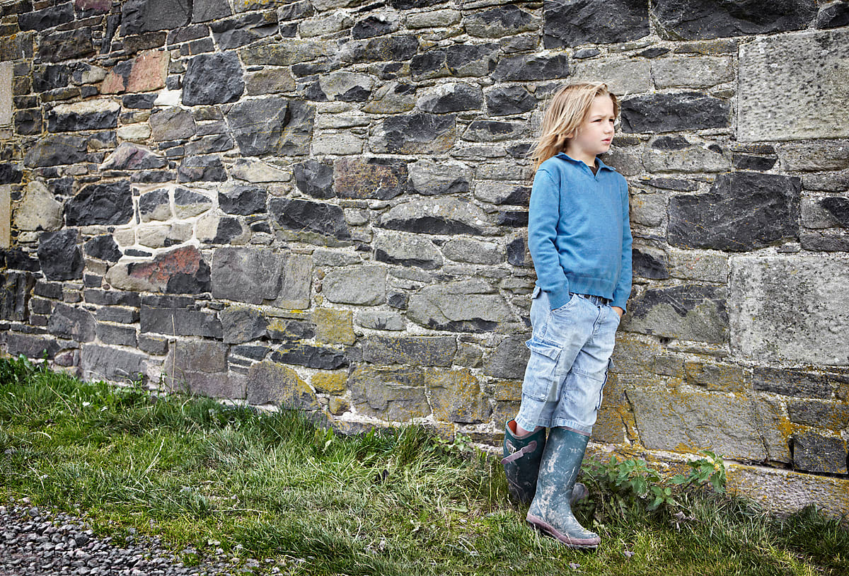 "A Boy Leans Against An Old Stone Wall" by Stocksy Contributor "James ...
