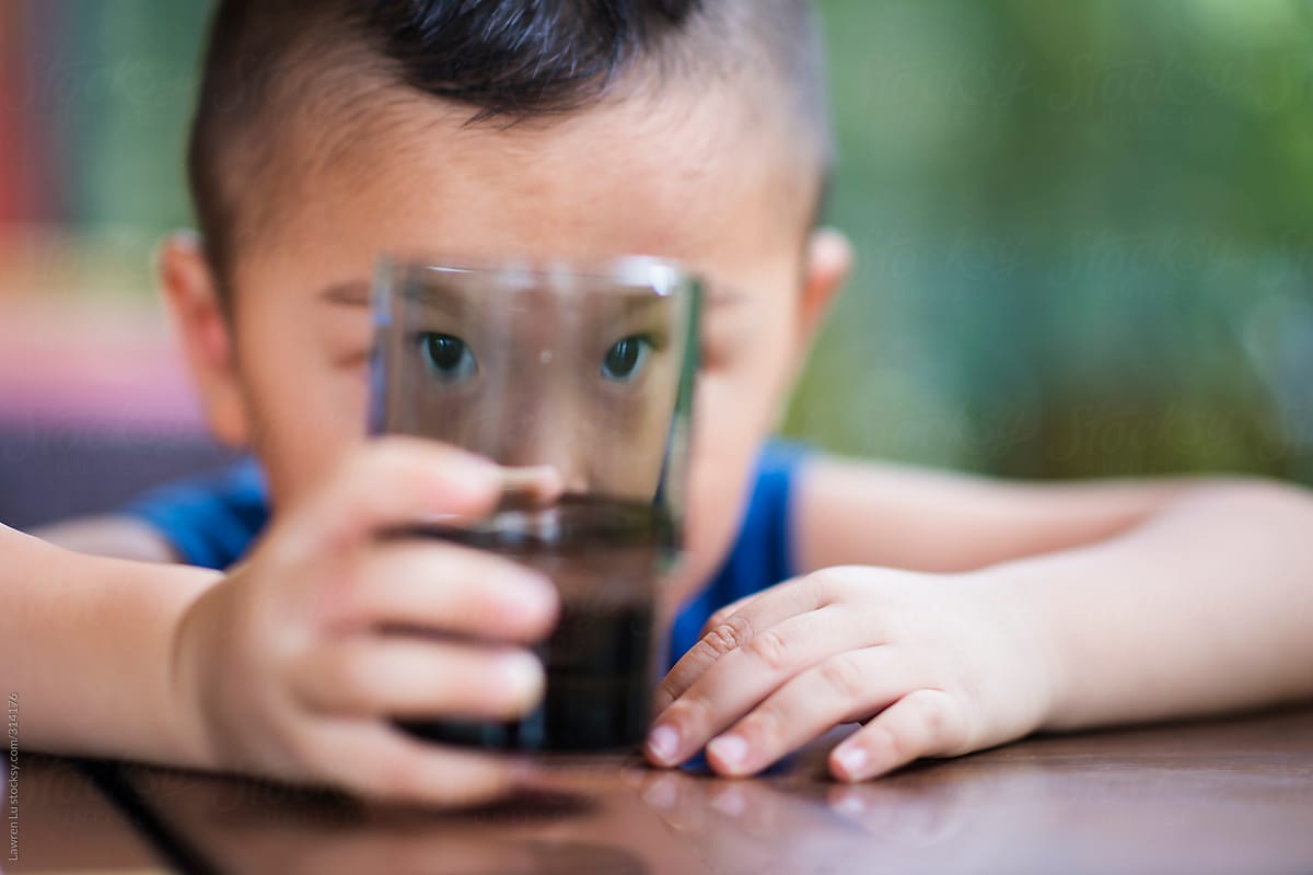 "Cute Boy Looking At Camera Through A Water Glass In Restaurant." by ...