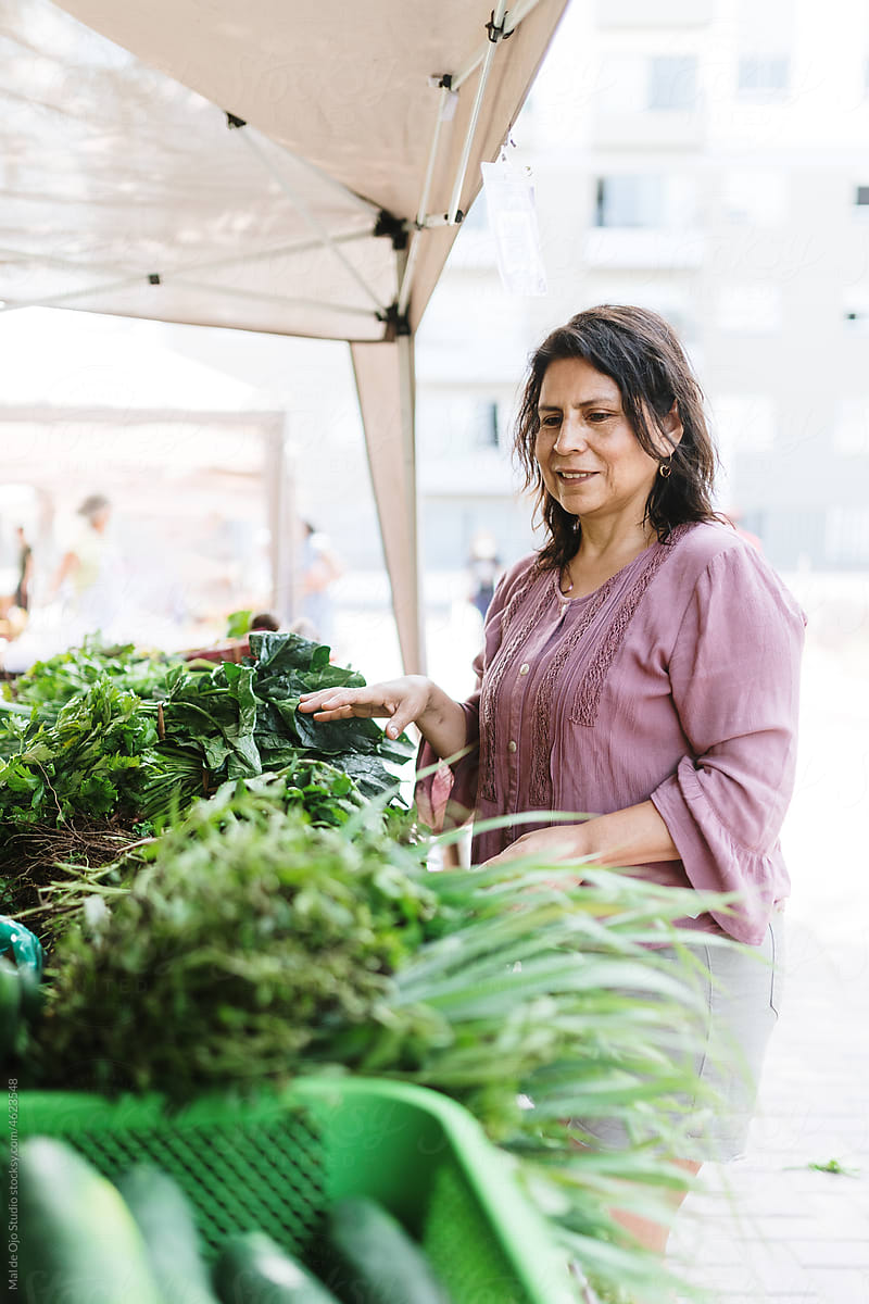 Smiling woman at an outdoors produce market - Stock Image - Everypixel