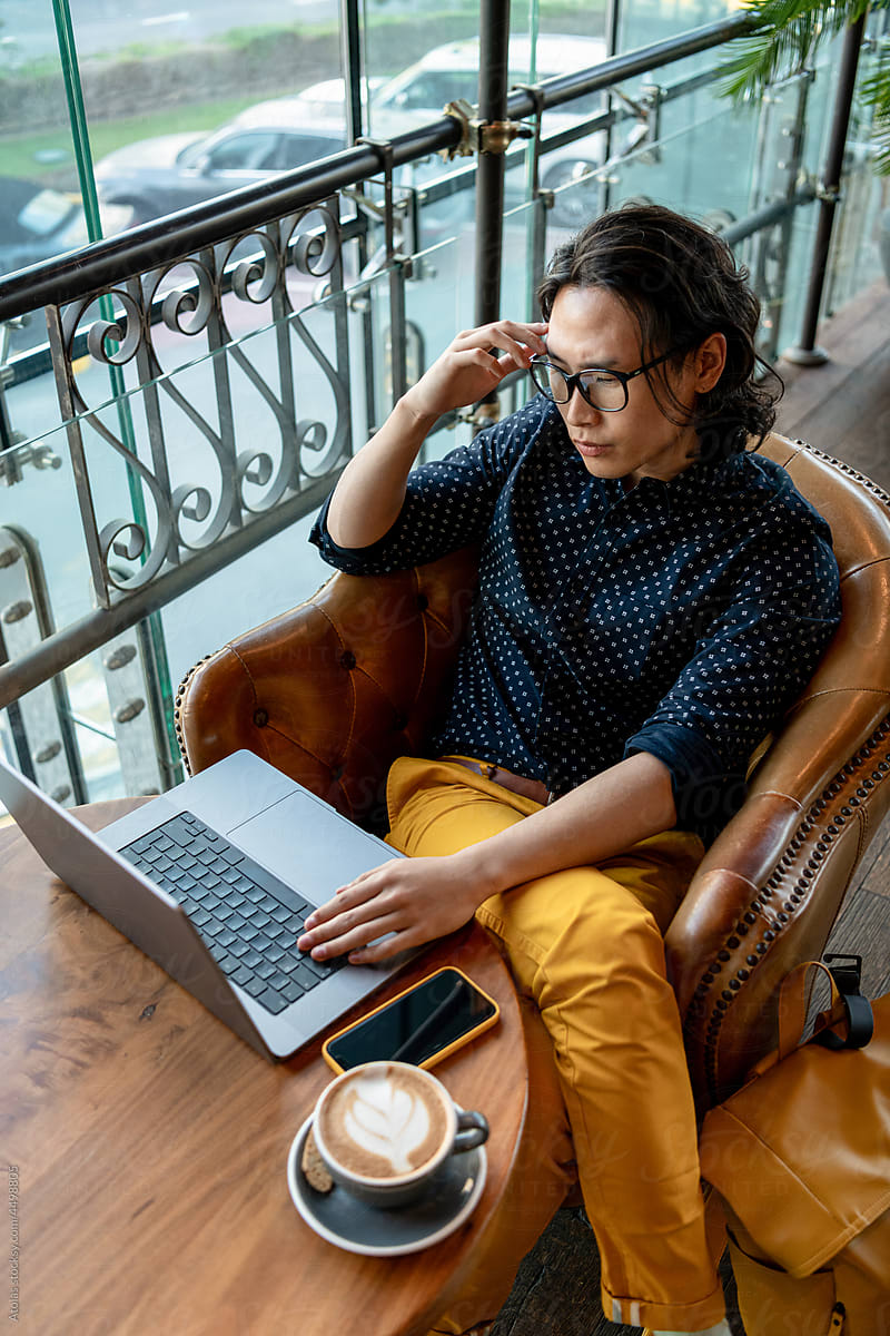 "Young Man Reading On Laptop" by Stocksy Contributor "Atolas" - Stocksy