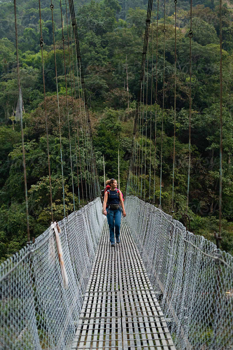 "Young Woman Crossing A Hanging Bridge During An Adventure Trekking In ...