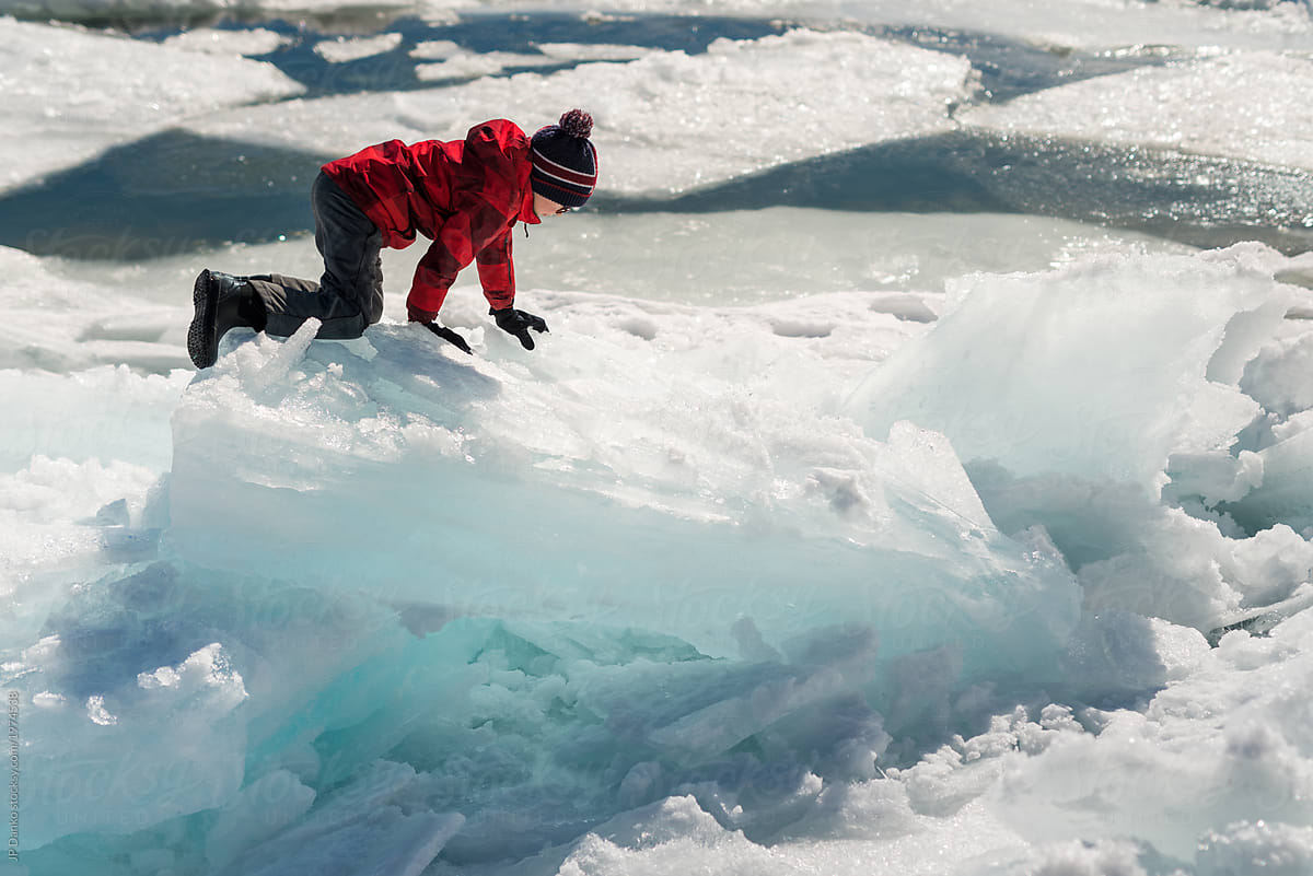 "Boy In Bright Winter Sunshine Climbs Across Ice Of Frozen Lakeshore ...