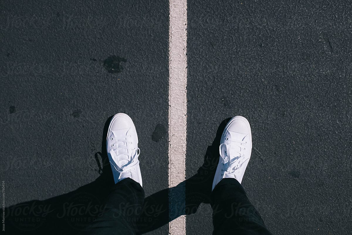 "Young Male Standing On Both Sides Of The Line Painted On Concrete In ...