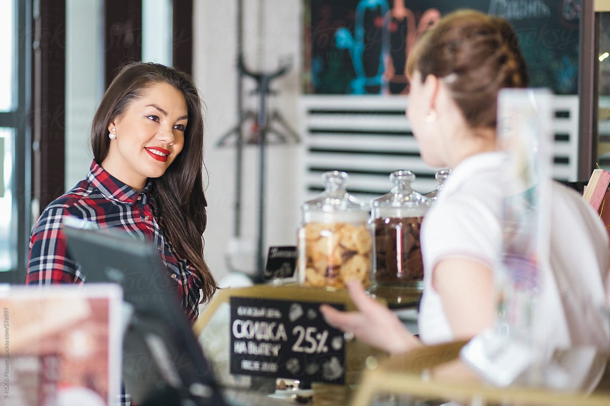 "Smiling Young Woman Talking With Cashier In Shop" by Stocksy ...