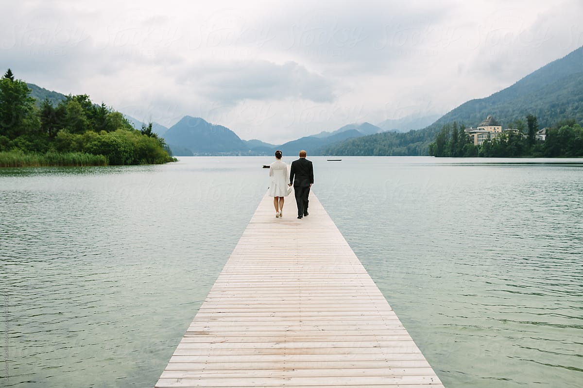 "Bridal Couple Walking On A Jetty At A Lake" by Stocksy Contributor ...