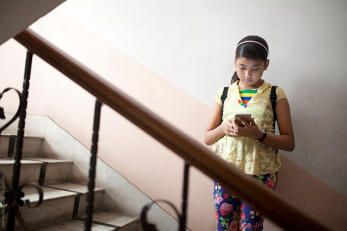"Teenage Girl Browsing Smartphone By Standing In A Stair Of A House" by ...