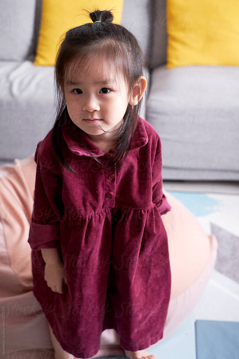 "Cute Asian Little Girl Facing The Camera, In Front Of The Sofa At Home ...