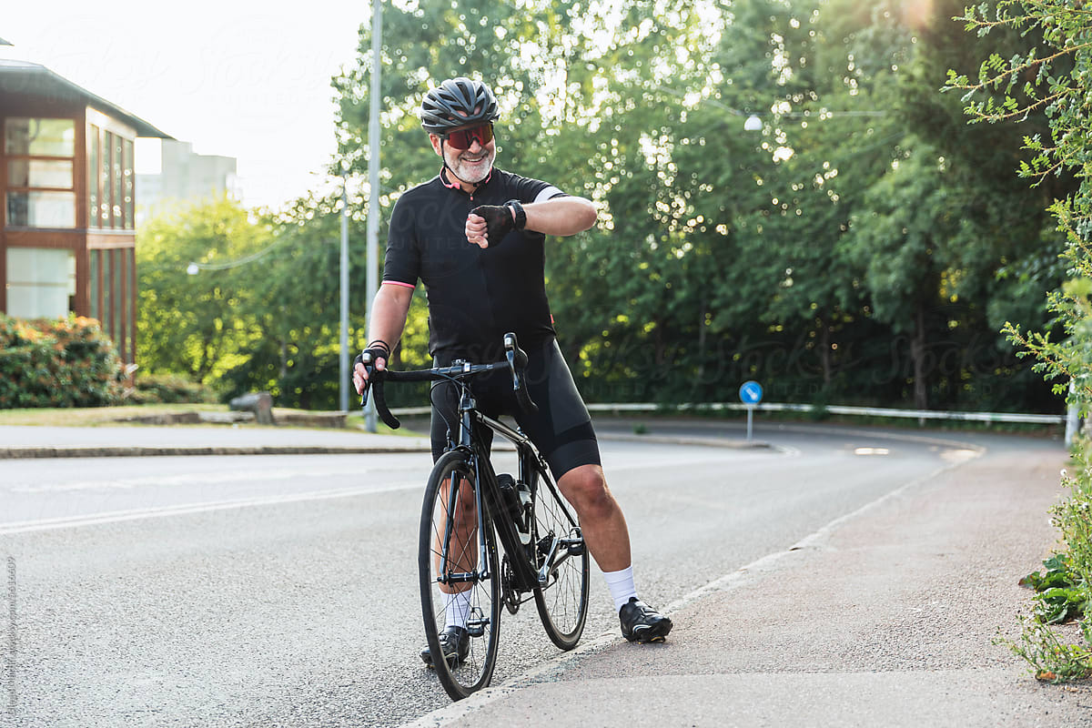 "Cyclist Checking Watch" by Stocksy Contributor "Diego Martin" - Stocksy
