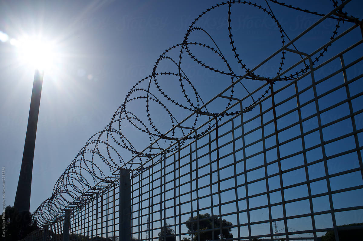 "Razor Wire Fence And Chimney Stack Against A Clear Blue Sky" by ...
