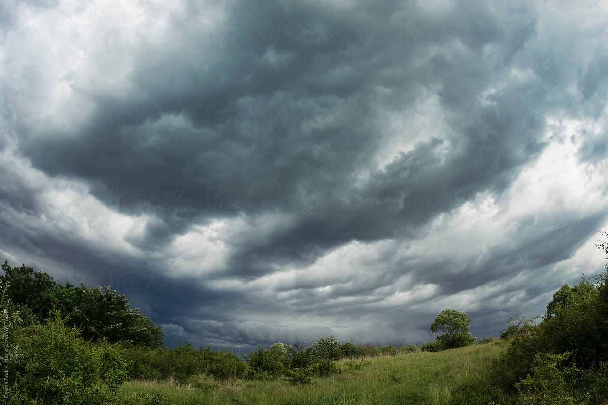 "Heavy Storm Clouds Over Green Landscape" by Stocksy Contributor "Cosma ...