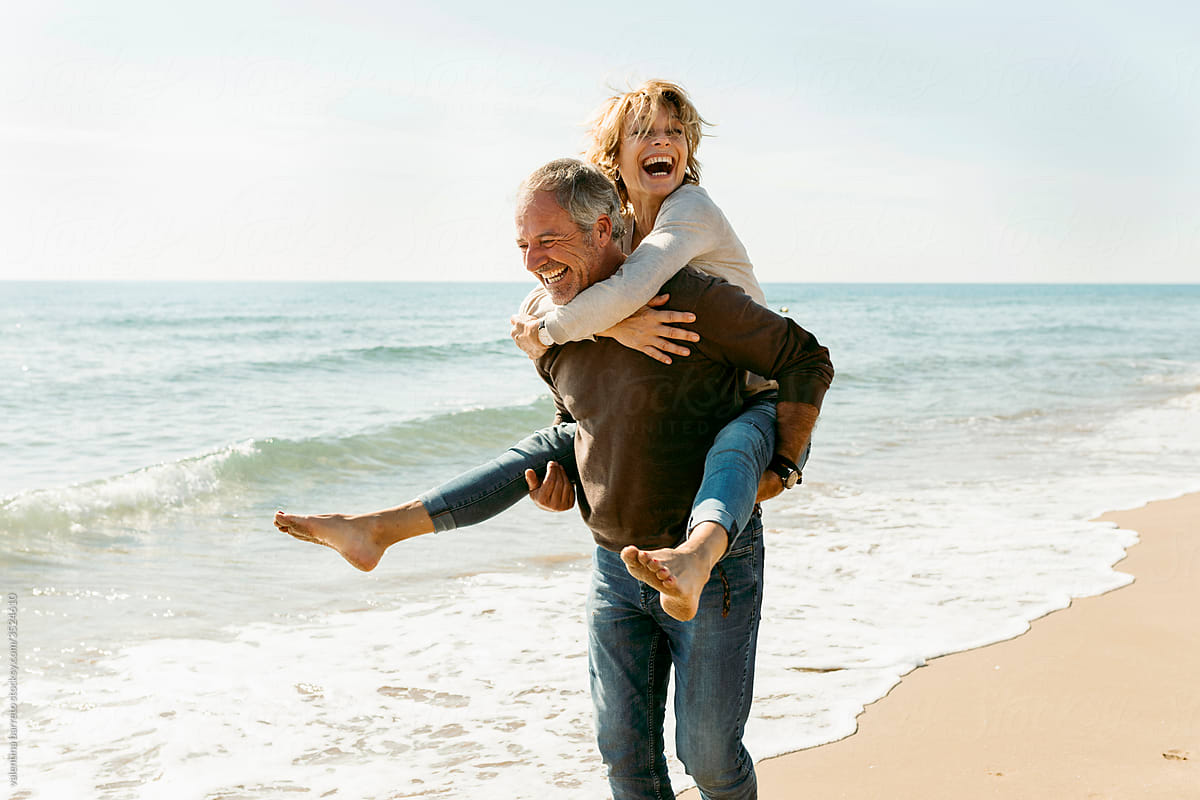 "Happy Couple Piggyback At The Beach" by Stocksy Contributor "valbar ...