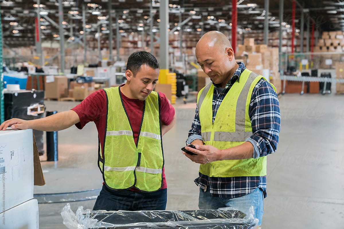 "Warehouse Workers Using Cell Phone" by Stocksy Contributor "Walter and ...
