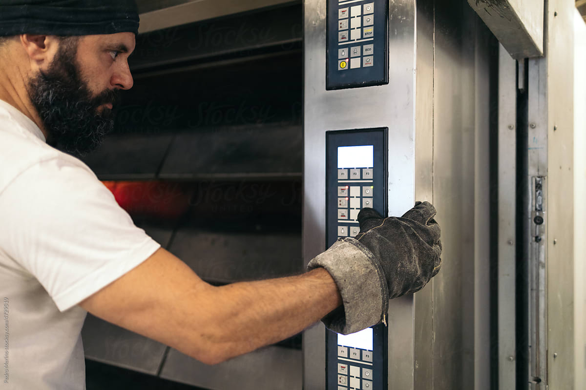 "Baker Turning On The Oven" by Stocksy Contributor "Pedro Merino" - Stocksy