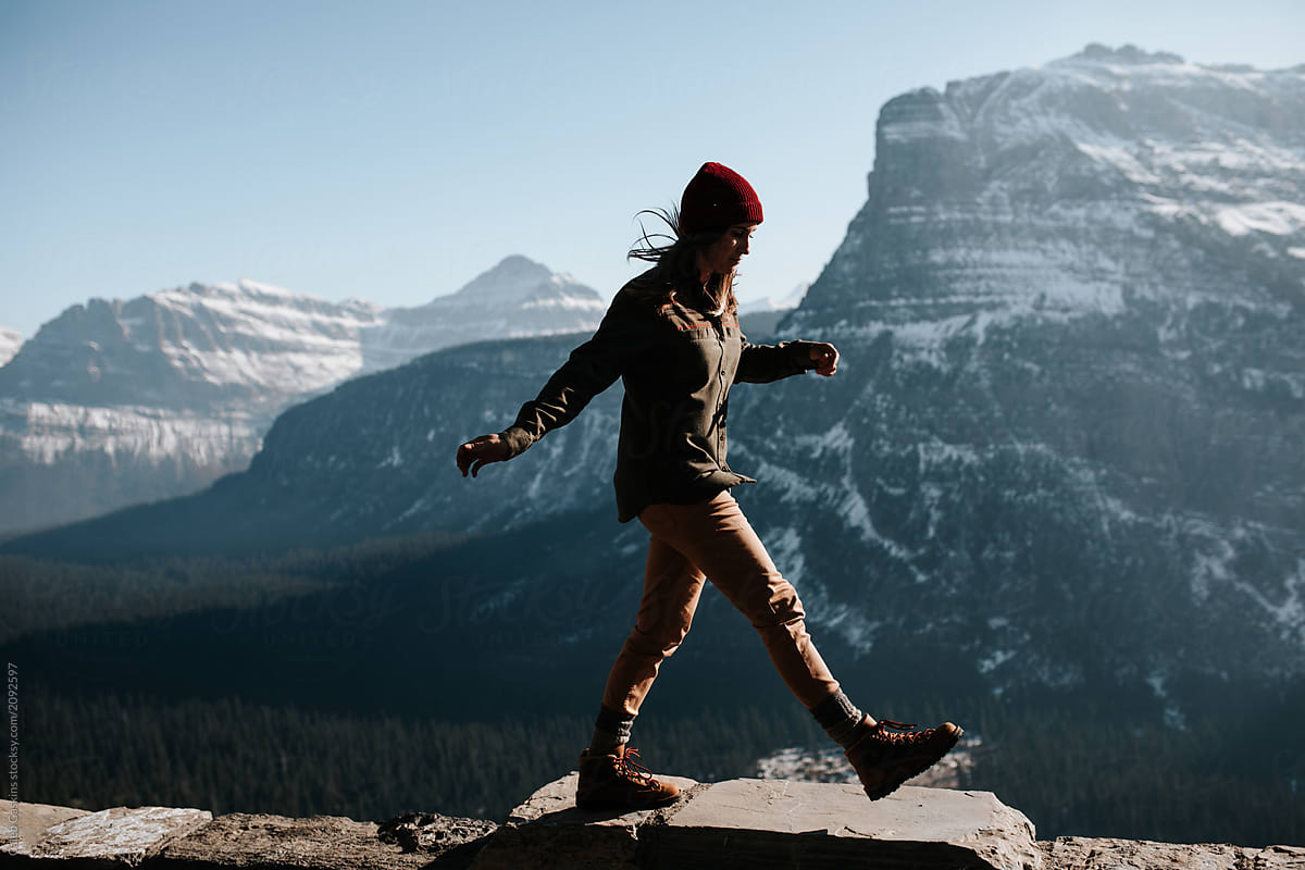 Woman walking along ledge - Stock Image - Everypixel