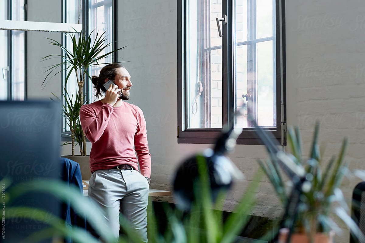 "Businessman Using Mobile Phone By Window In New Office" by Stocksy ...