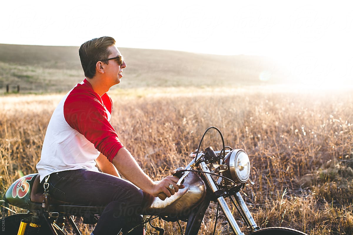 "Young Stylish Man On A Custom Built Motorcycle Looking Out On A Meadow ...