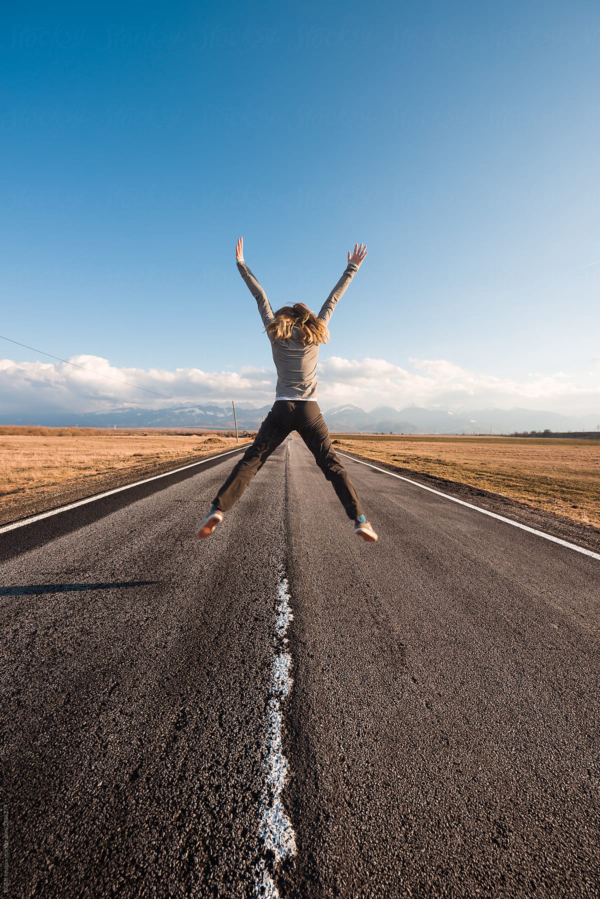 "Young Woman Celebrating Life Jumping In Midair On Empty Driveway" by ...