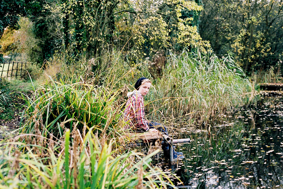 "Boy Sitting On A Jetty By A Lake" by Stocksy Contributor "Helen ...
