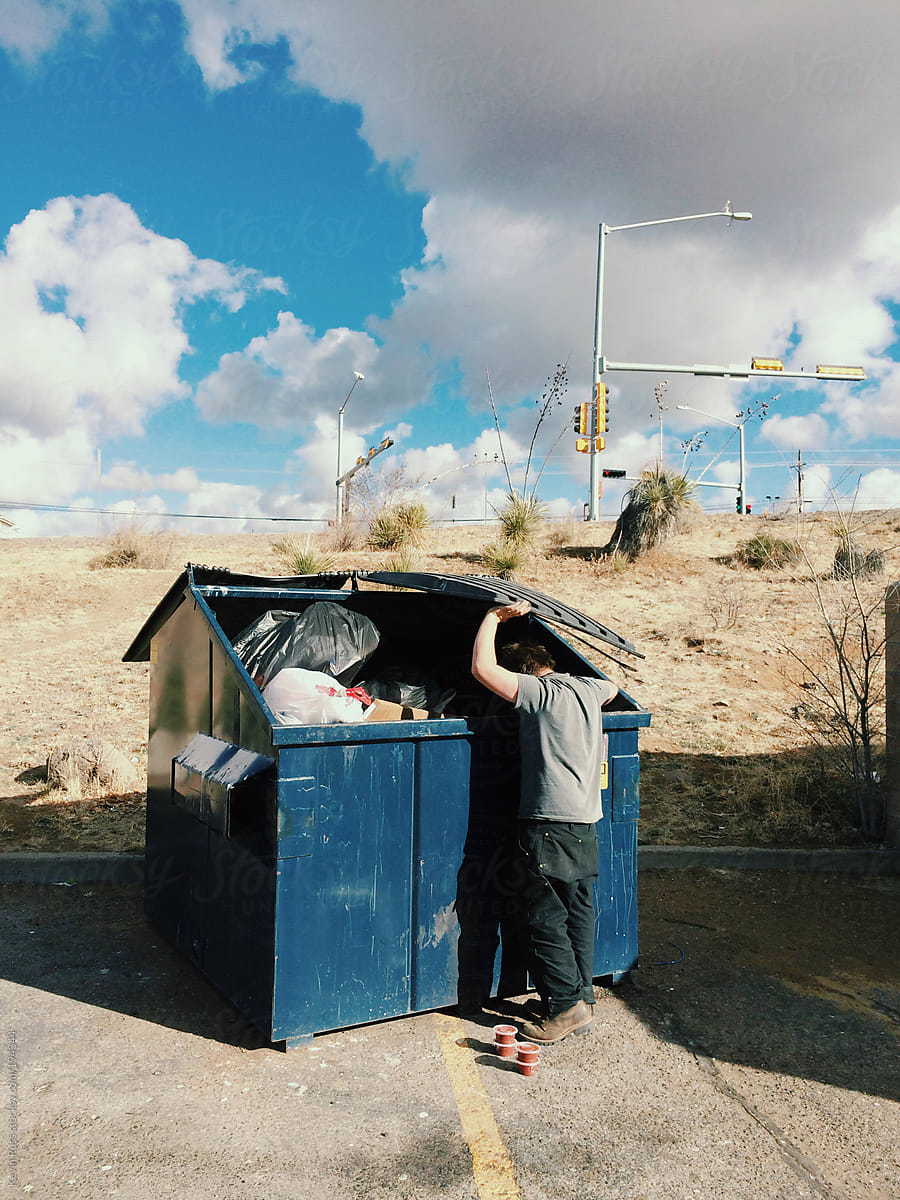 "Man Looking In Dumpster" by Stocksy Contributor "Kevin Russ" - Stocksy
