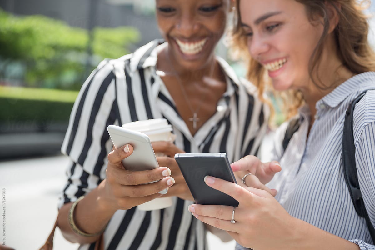 "Women Smiling While Holding Smartphones" by Stocksy Contributor "Jovo ...