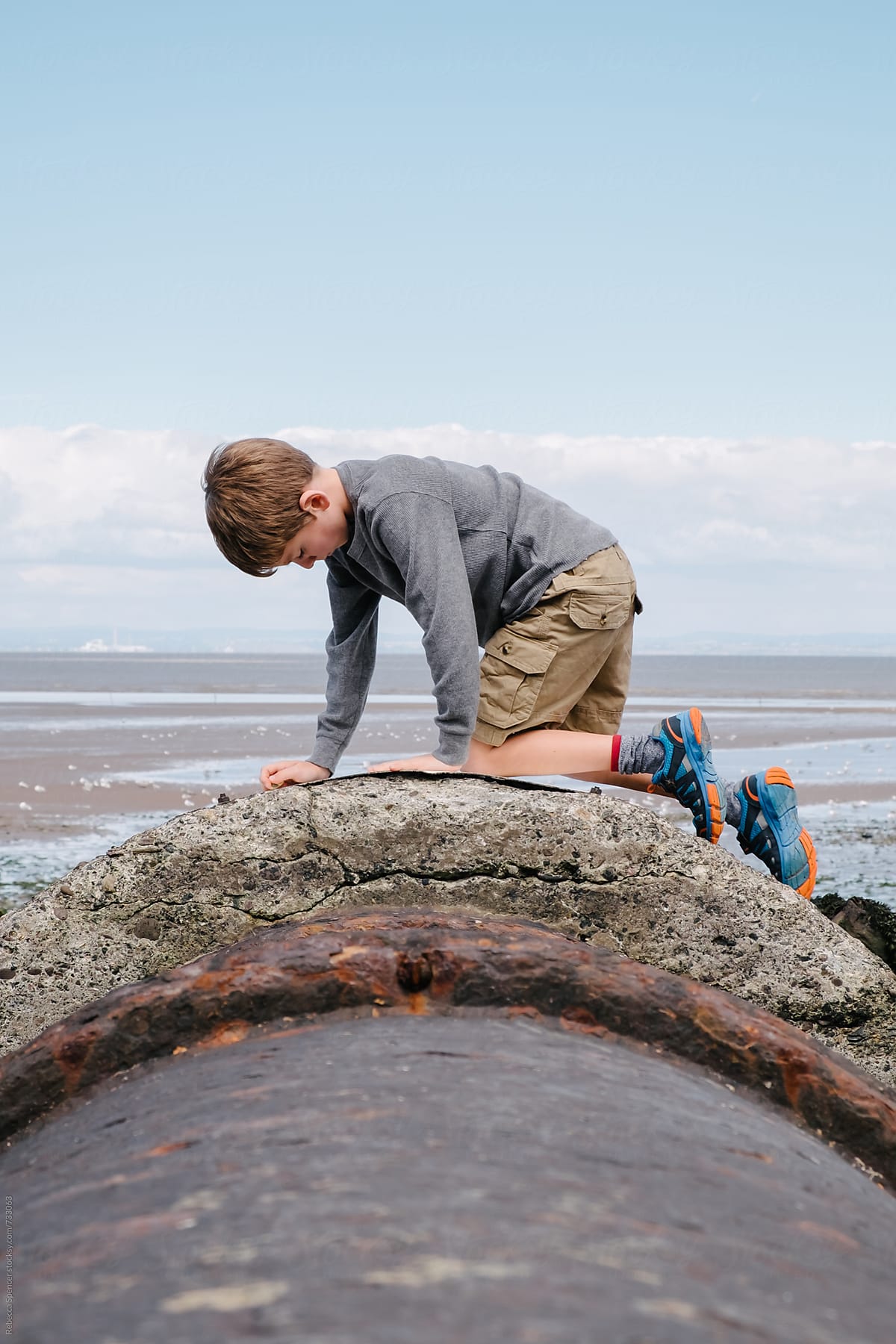 "Boy Looking Into Old Pipe On Beach" by Stocksy Contributor "Rebecca ...