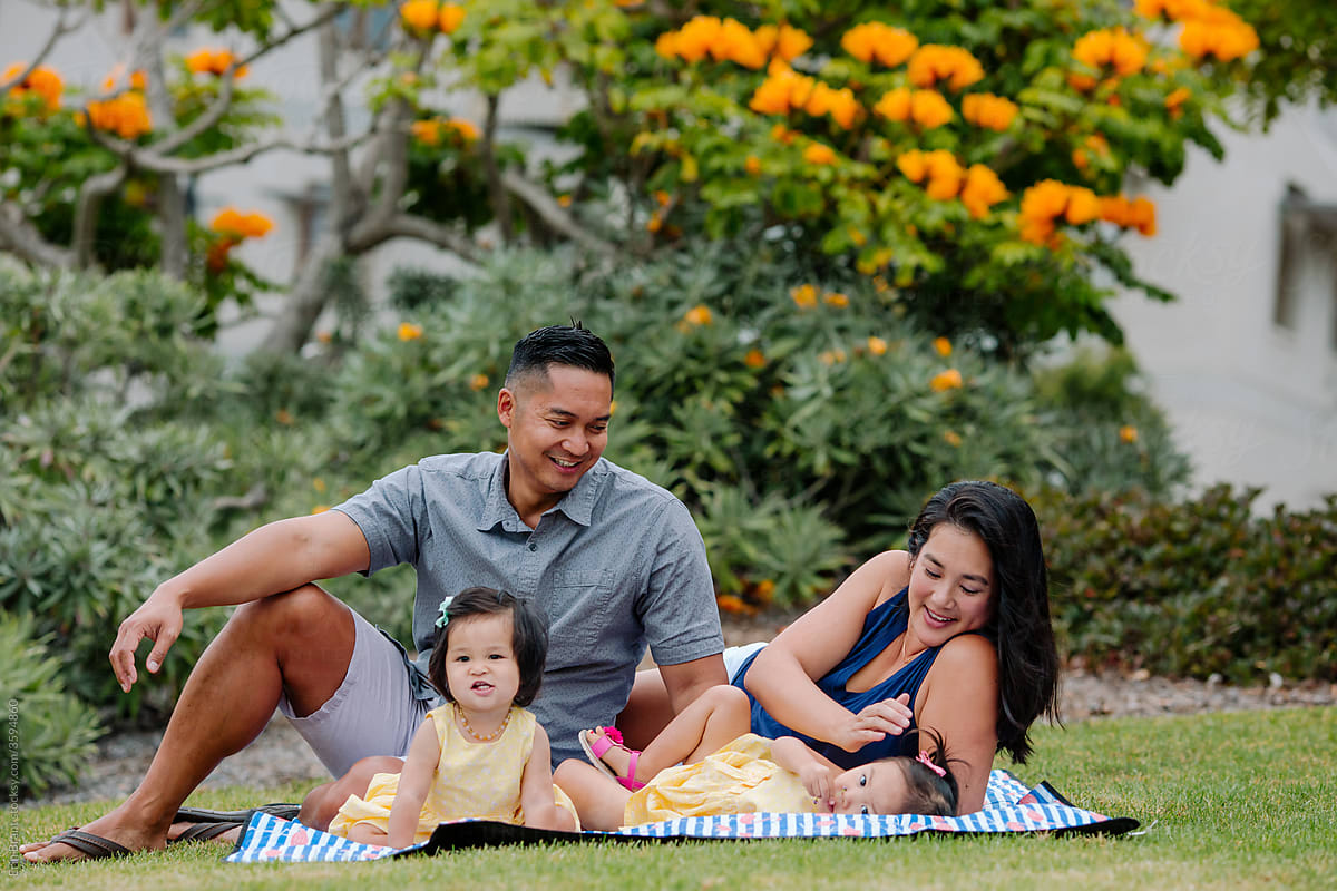 Happy young asian family outdoors on blanket - Stock Image - Everypixel