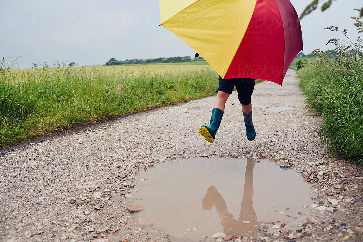 "Child Having Fun Playing Outdoors On A Rainy Day With An Umbrella" by ...