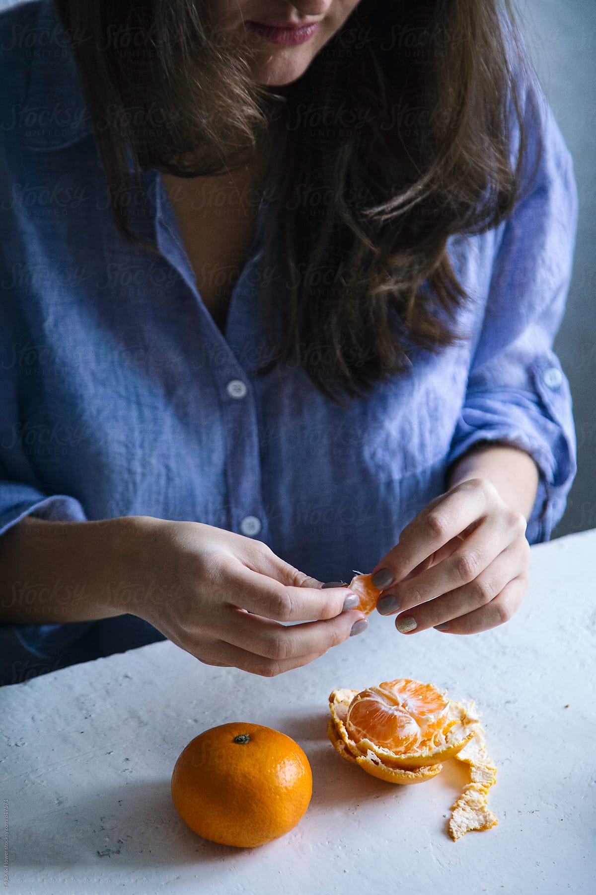 "Woman Peeling Tangerines" by Stocksy Contributor "Danil Nevsky" - Stocksy