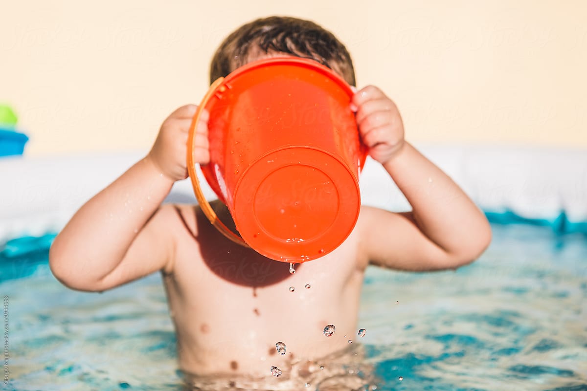 "Toddler Playing With A Bucket In A Small Wading Pool Outdoors" by ...