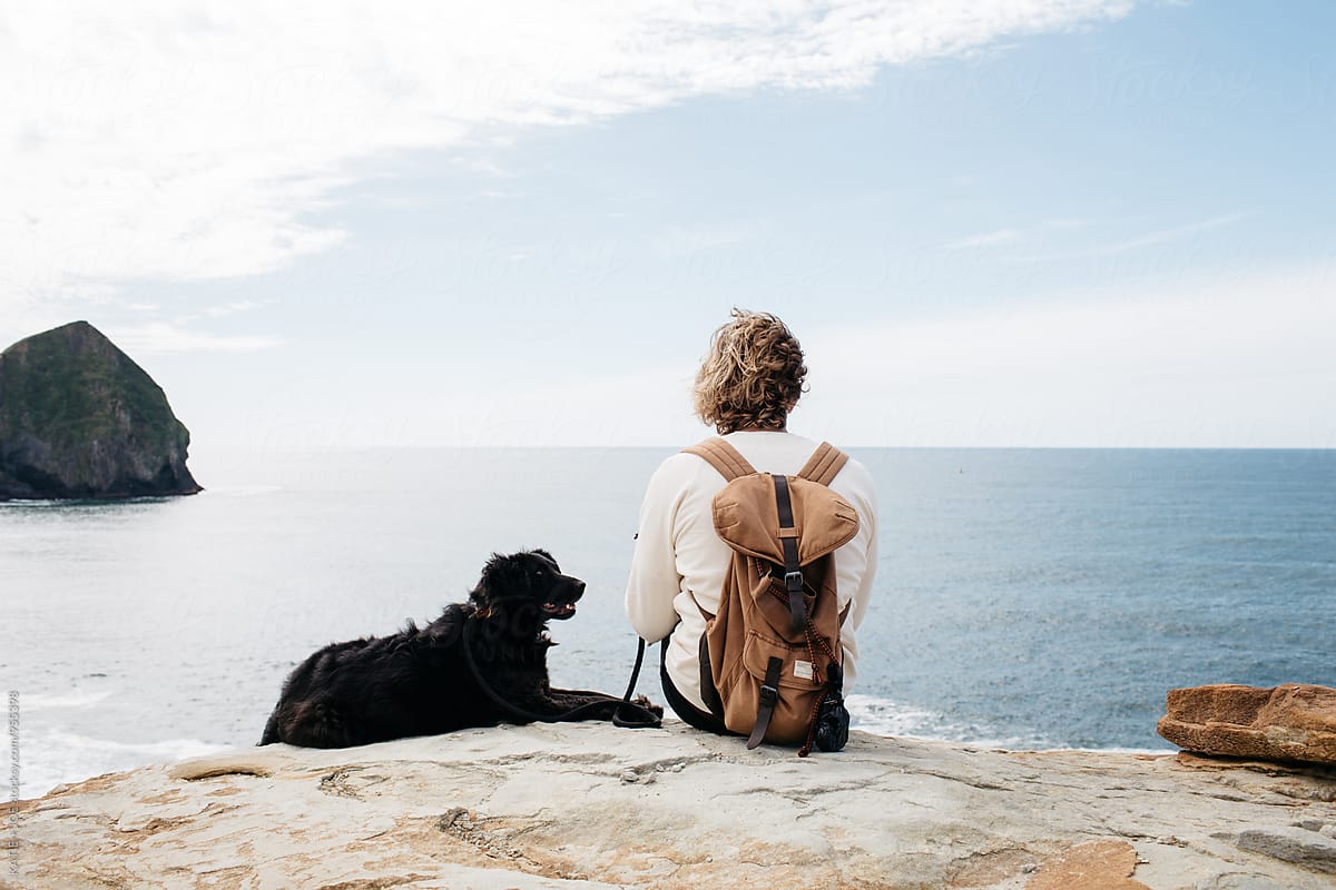 "Man And Dog Sitting On A Cliff Overlooking The Ocean" by Stocksy ...