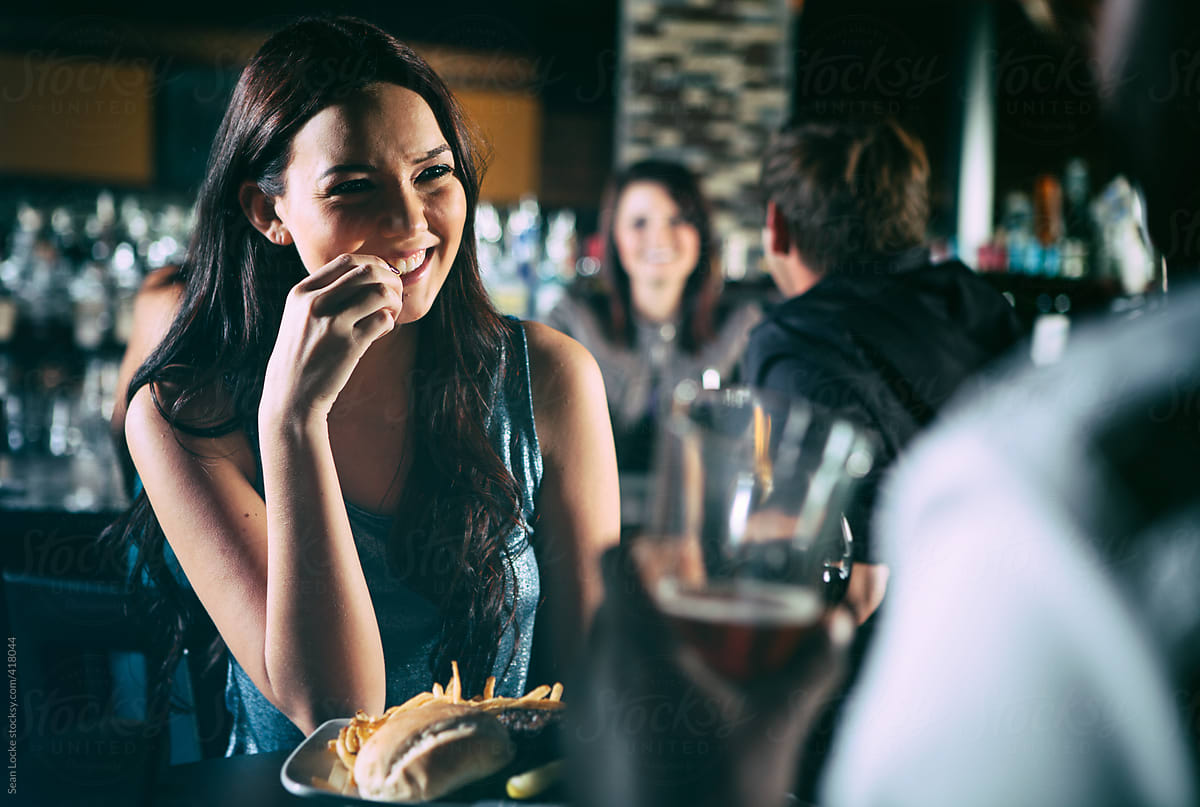 "Bar: Woman Laughing While Eating Burger And Fries" by Stocksy ...