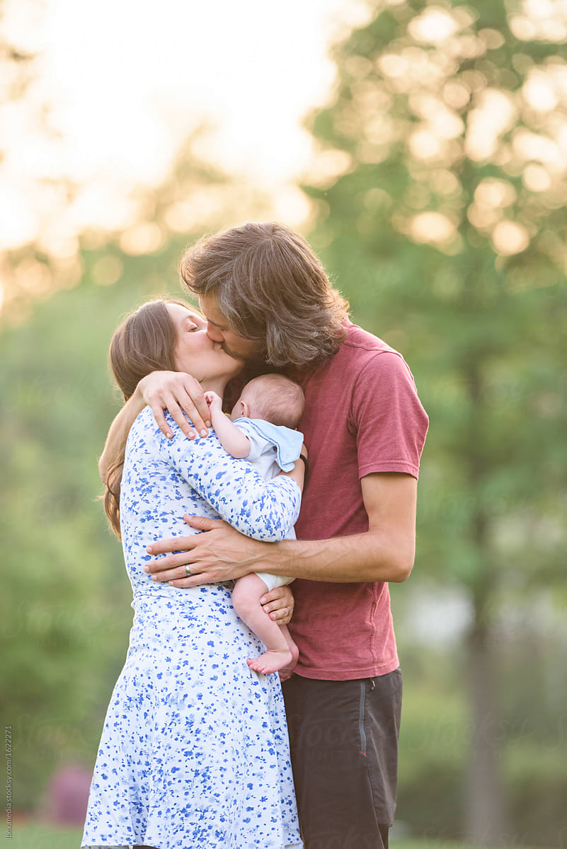 "Parents Kissing Holding Tenderly Their Infant Baby Boy" by Stocksy ...