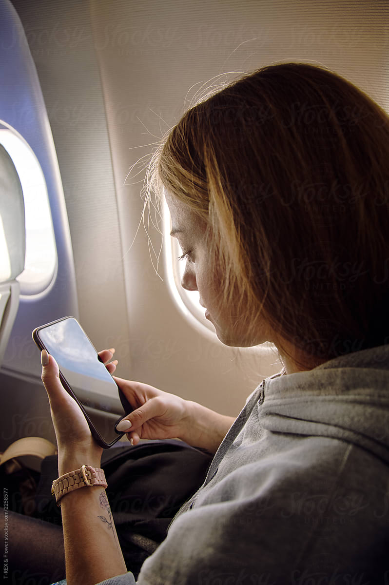 "Young Woman Using Smartphone In Plane" by Stocksy Contributor "Danil ...