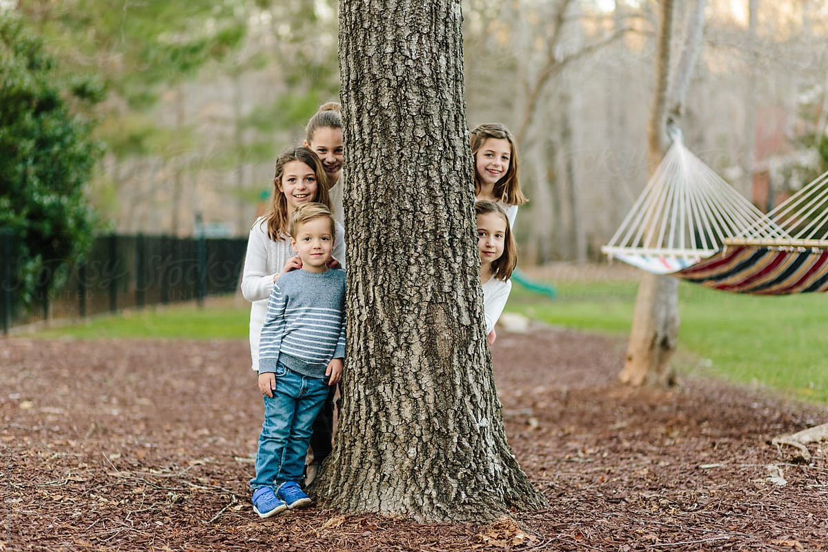 "A Group Of Kids Peeking Out From Behind A Tree" by Stocksy Contributor ...