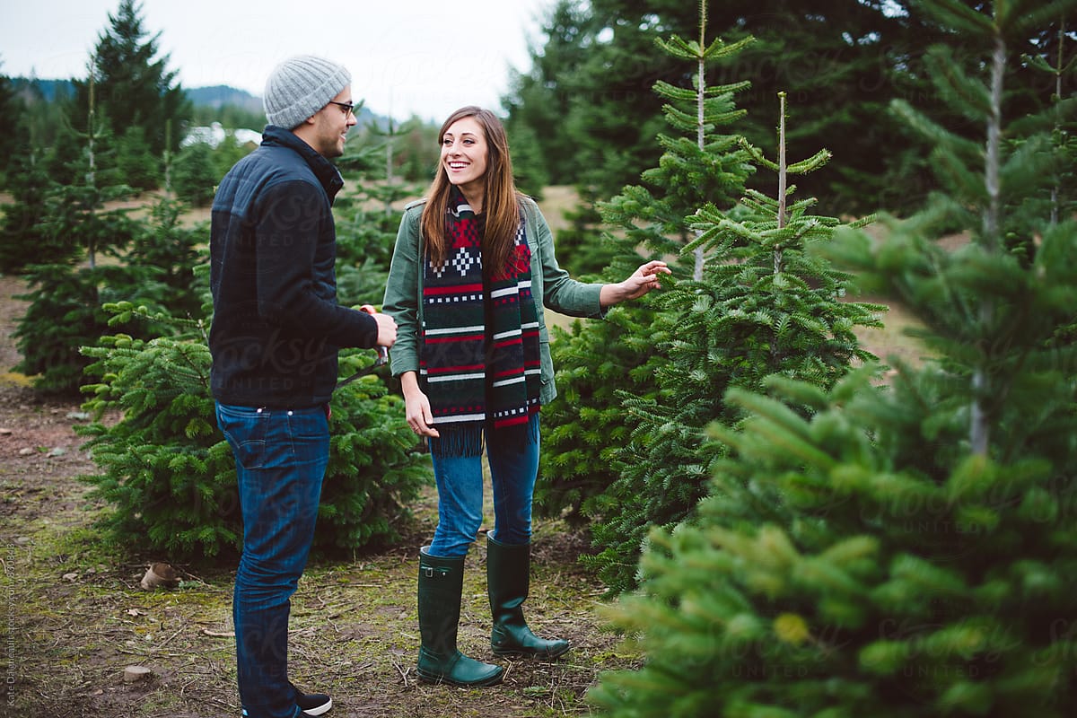 "Attractive Young Couple Cutting Down Their Christmas Tree." by Stocksy ...