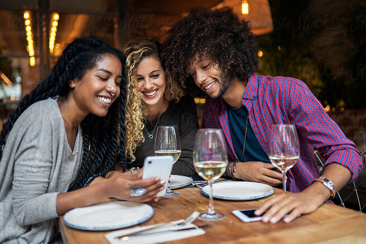 "Happy Friends Using Phone" by Stocksy Contributor "Santi Nuñez" - Stocksy