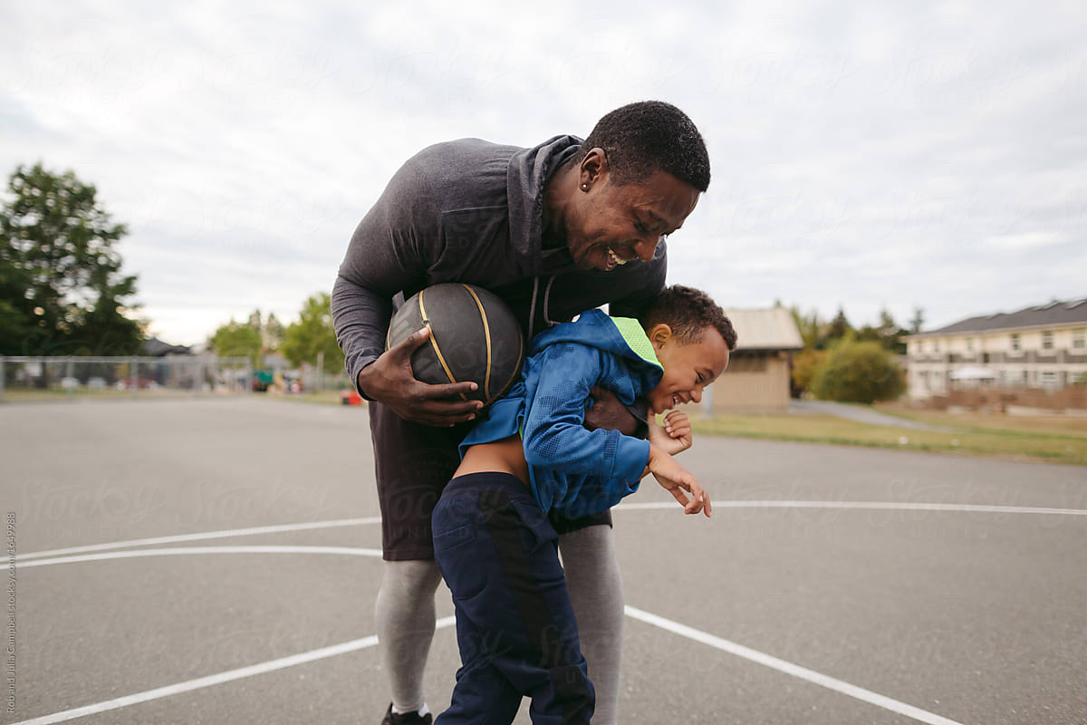 "Dad And Son Having Fun On Outdoor Basketball Court Together" by ...