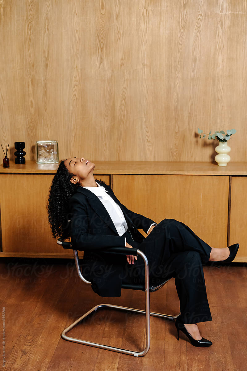 "Businesswoman Reclining In Chair Against Wooden Wall" by Stocksy ...