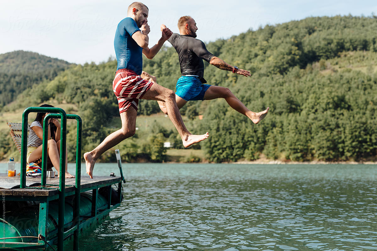 Friends Goofing Around While Jumping Into The Lake - Stock Image ...