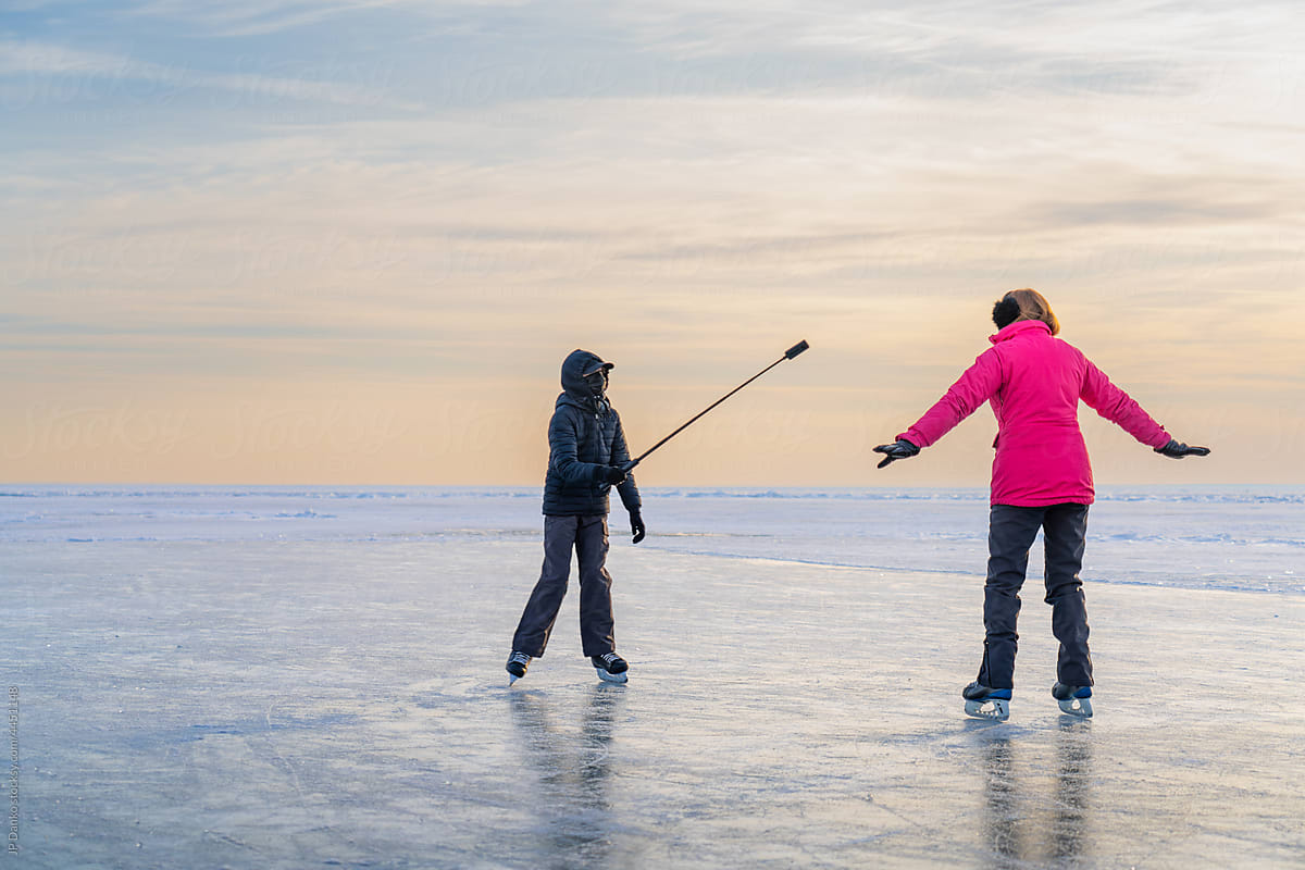 Skating with Selfie Stick on Frozen Lake in Winter at Dusk - Stock ...