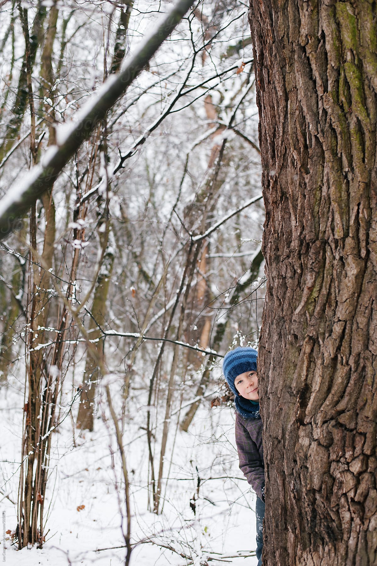 "Boy Playing Hide-and-seek In A Snowy Forest." by Stocksy Contributor ...