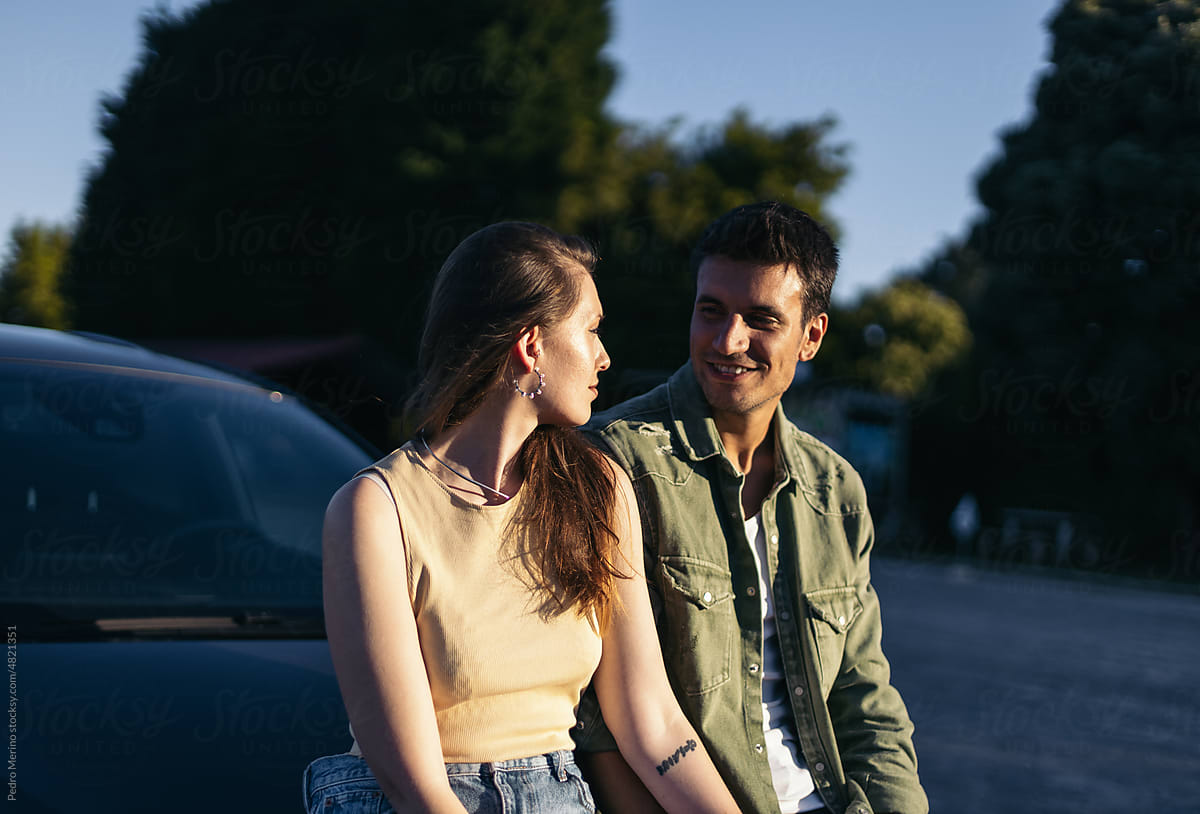 Couple leaning on car at sunset - Stock Image - Everypixel
