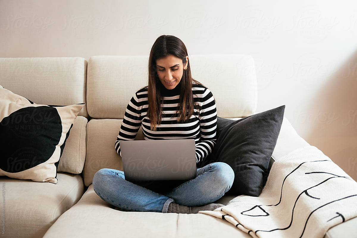Focused woman working on computer on couch - Stock Image - Everypixel