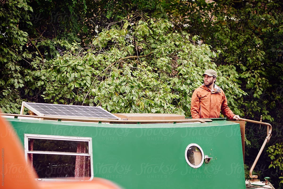 "Man Driving His Canal Boat" by Stocksy Contributor "Aila Images" - Stocksy