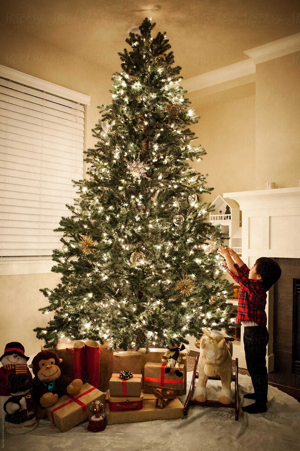 "Cute Asian Boy Putting On Ornament On A Christmas Tree" by Stocksy ...