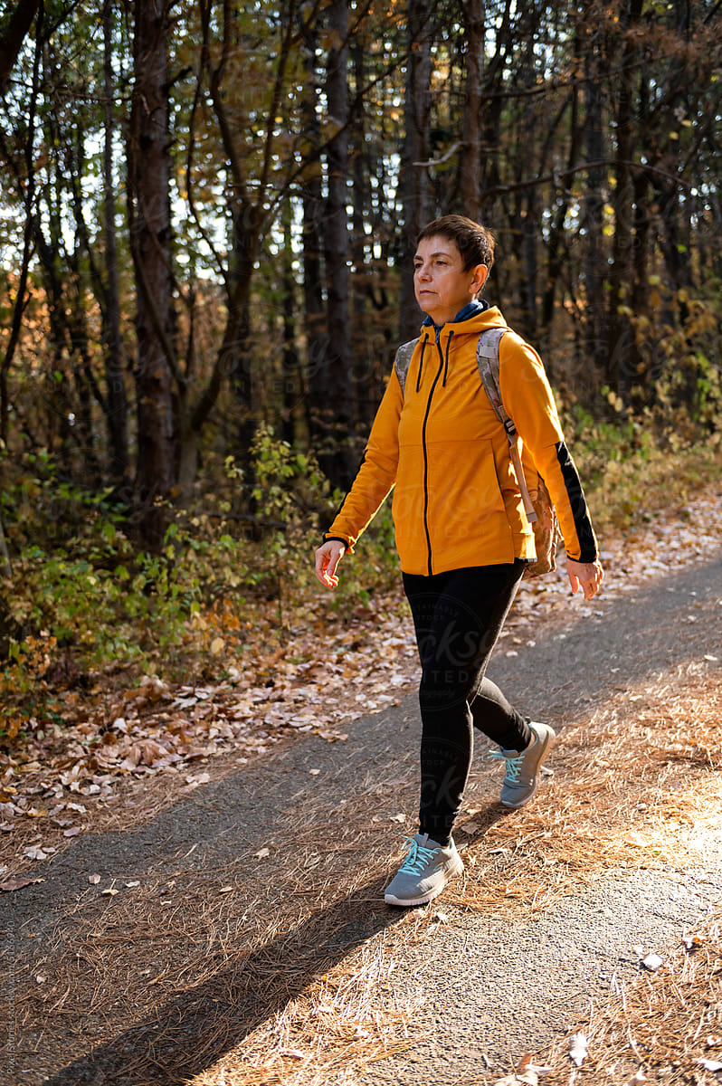 Middle-aged woman walking/hiking in forest - Stock Image - Everypixel
