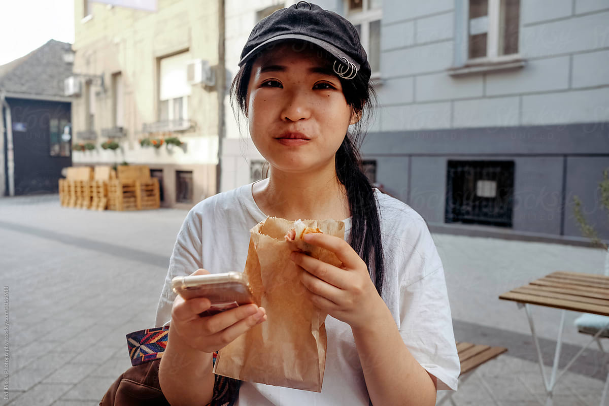 "Young Woman Eating Baked Good On The Street" by Stocksy Contributor ...