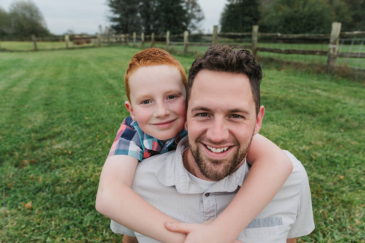 "Playful Father Smiling With Young Son In Farm Field" by Stocksy ...