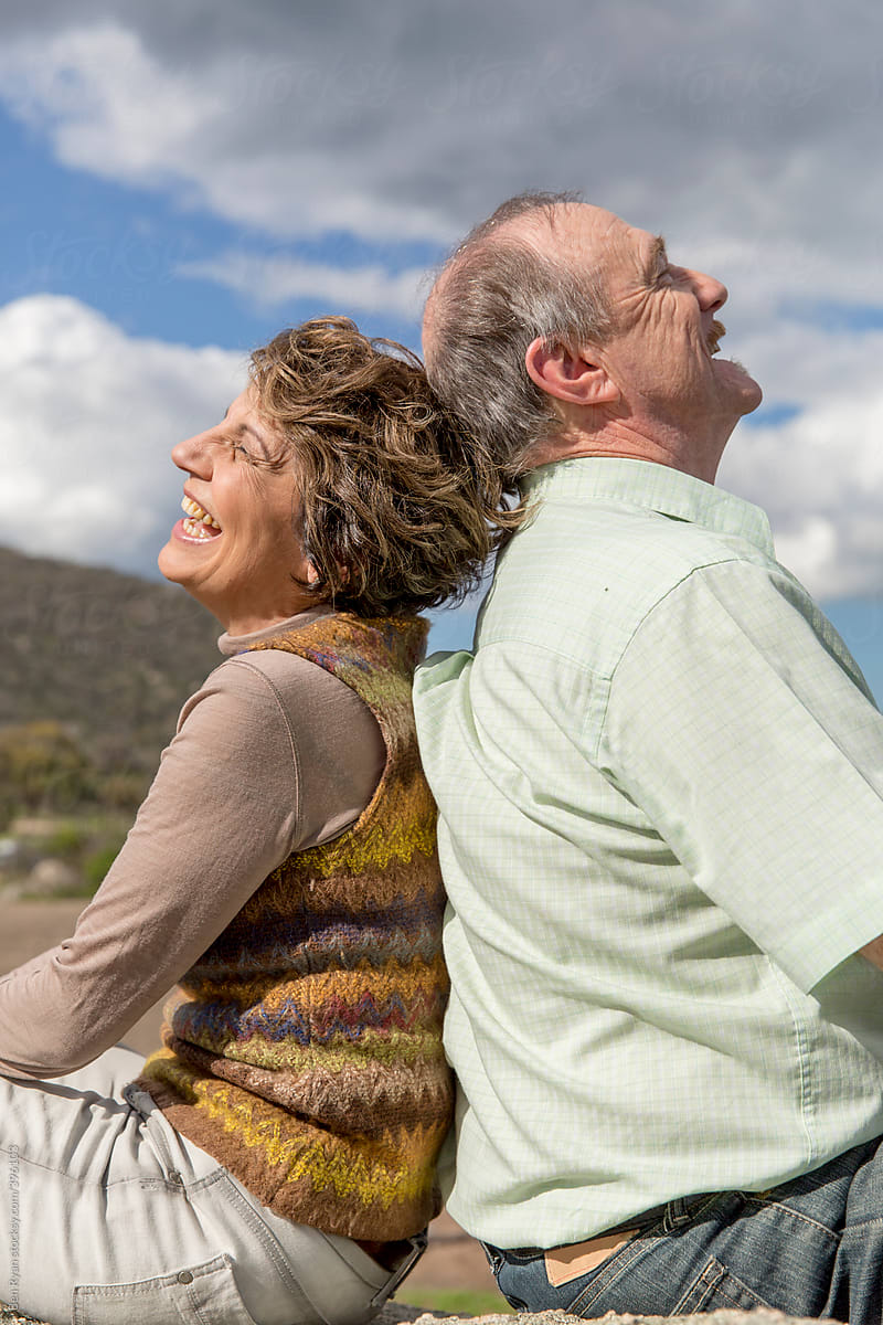 "Grey Nomad Couple Sitting Back To Back Laughing Heartily" by Stocksy ...