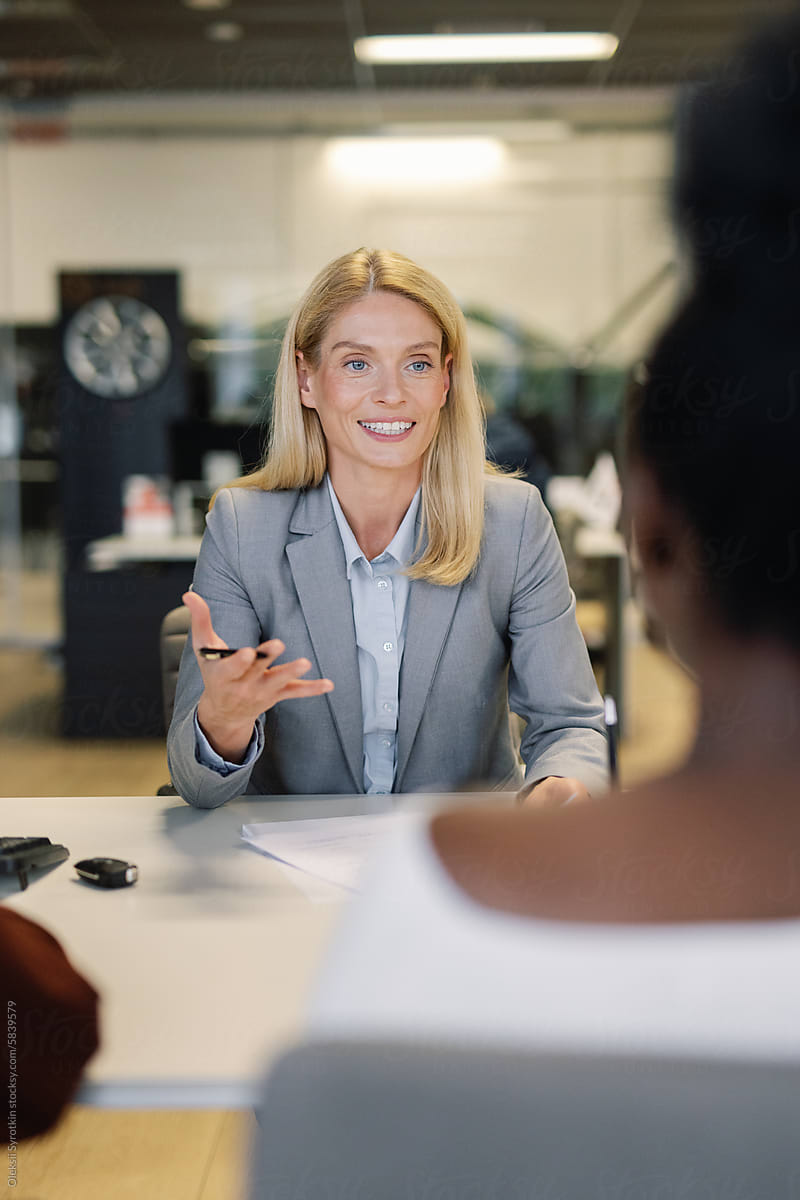 "Sales Representative Talking To Female Client In Car Dealership Office ...